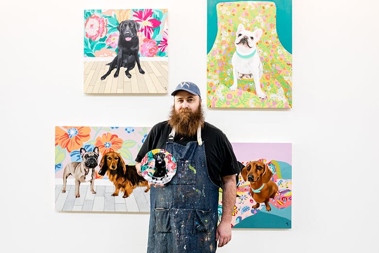 An artist with a beard standing in front of paintings of dogs. - This ...
